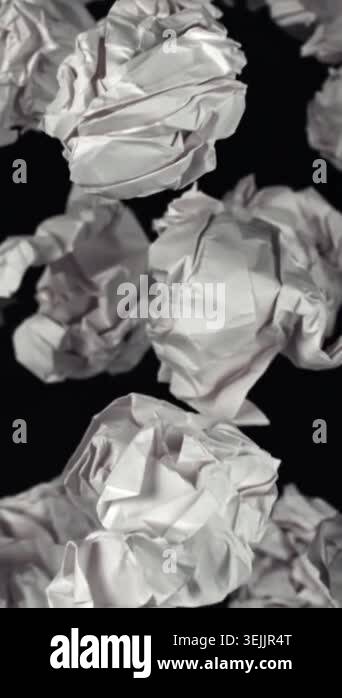 Crumpled paper flies and falls on a black background. Filmed on a high ...