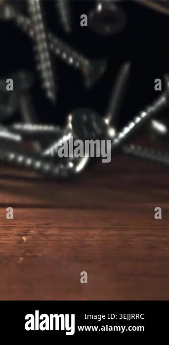 Self-tapping screws fall on a wooden table. Filmed on a high-speed ...