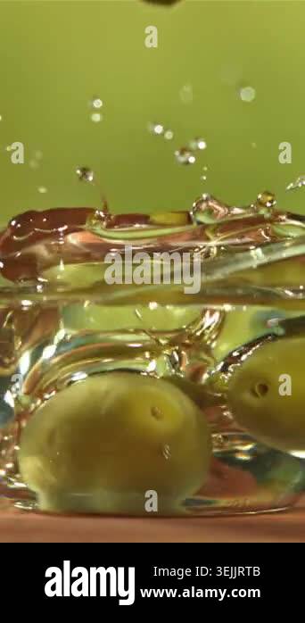 The olives fall into a cup of oil. Filmed on a high-speed camera at ...