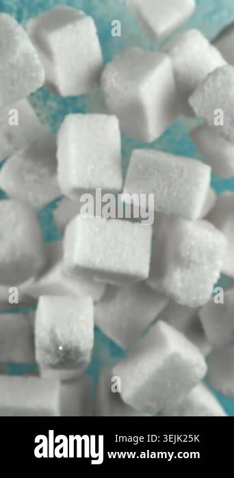 Cubes of sugar fly up and fall down on a blue background. Filmed on a ...