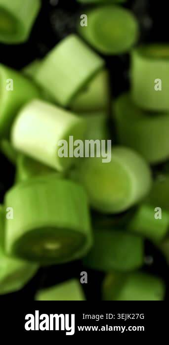 Sliced leeks flying on a black background. Filmed on a high-speed ...