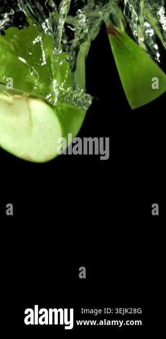 Pieces of green apples fall under the water. Filmed on a high-speed ...