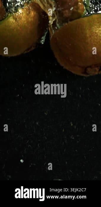 Sliced kiwi falling underwater on a black background. Filmed on a high ...