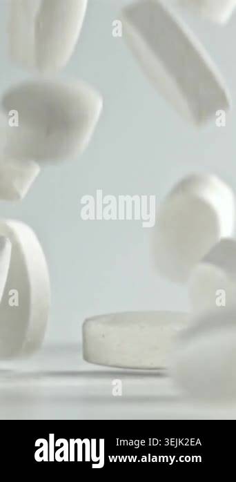 White tablets leap and tumble across cool metal plane, dramatic Filmed ...