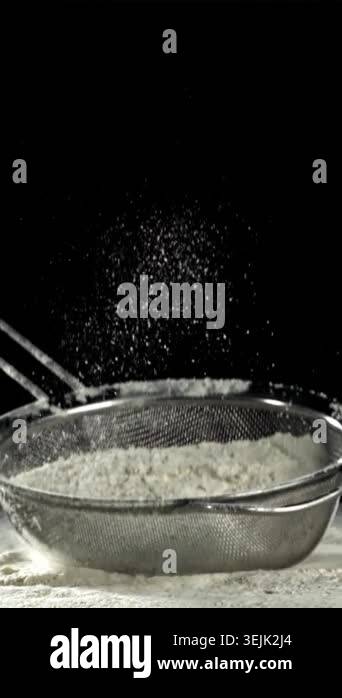 A sieve of flour falls on the kitchen table. Filmed on a high-speed ...