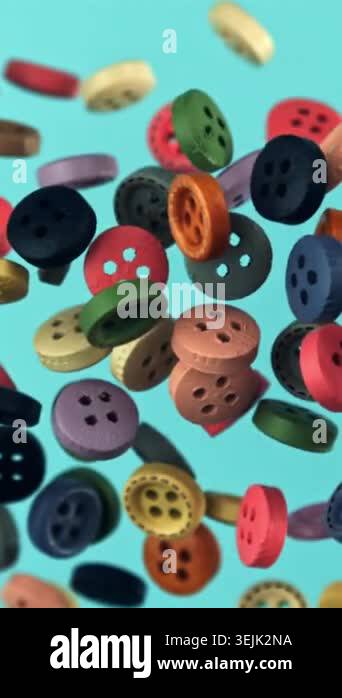 Multi-colored buttons fly on a blue background. Filmed on a high-speed ...