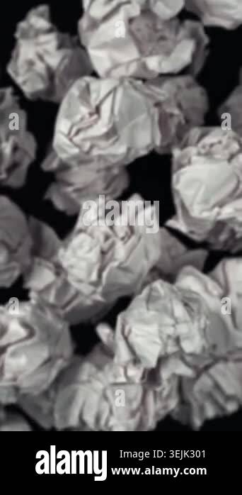 Crumpled paper flies and falls on a black background. Filmed on a high ...