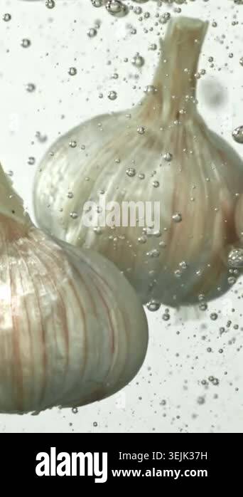 The heads of fresh garlic fall under the water. Filmed on a high-speed ...