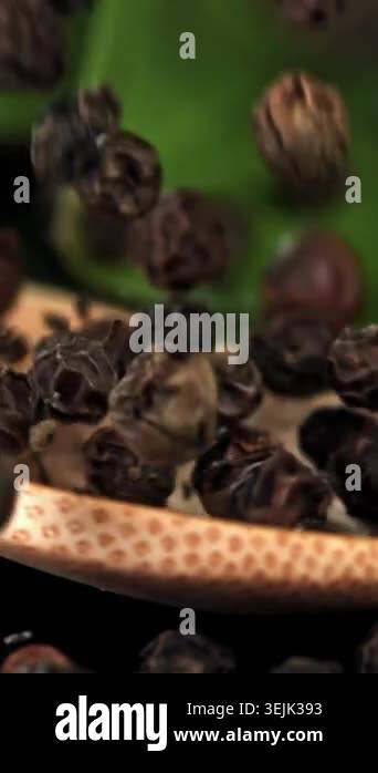 Black pepper falls on a wooden spoon. Filmed on a high-speed camera at ...
