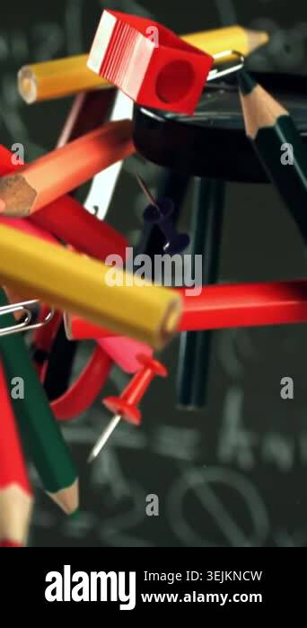 Multi-colored pencils flying against the background of a blackboard ...