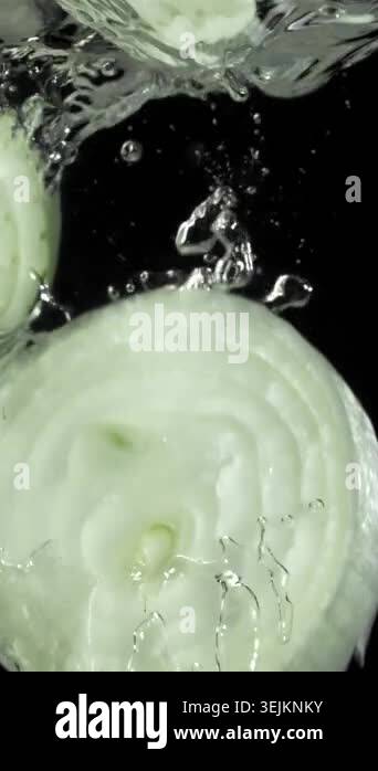 Sliced onion falling into water on black background. Filmed on a high ...