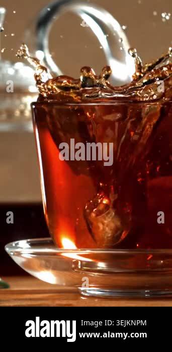 A piece of sugar falls into a mug of black tea. Filmed on a high-speed ...