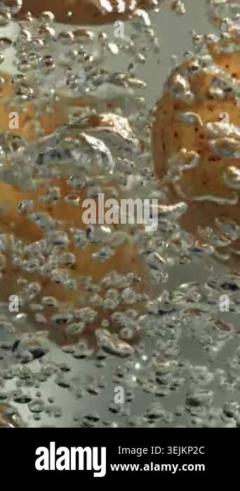The potatoes fall under the water into a saucepan. Filmed on a high ...