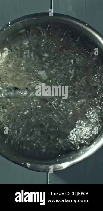 Water is poured into a saucepan. View from above. Filmed on a high ...
