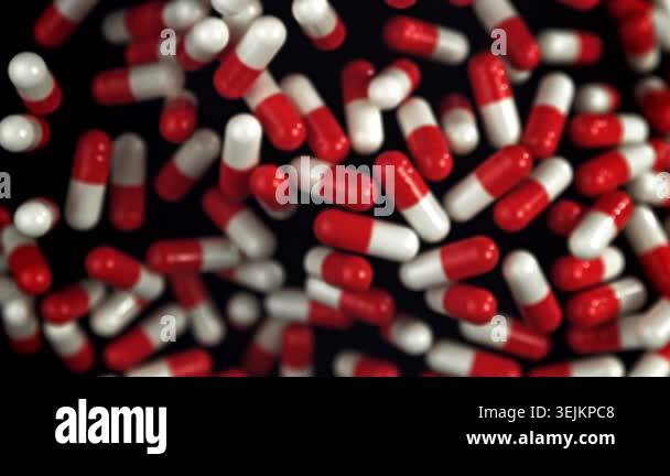 Storm of red and white capsules on black background, dynamic closeup ...