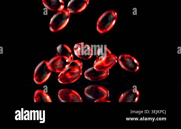 Red gel capsules on black surface, dramatic lowkey lighting Filmed on a ...