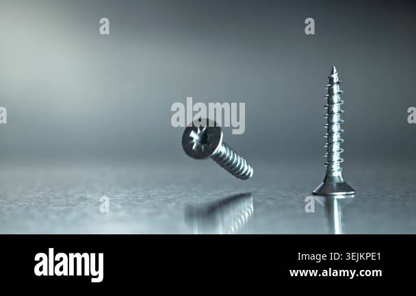 Closeup steel screws with one screw standing upright amid scattered ...