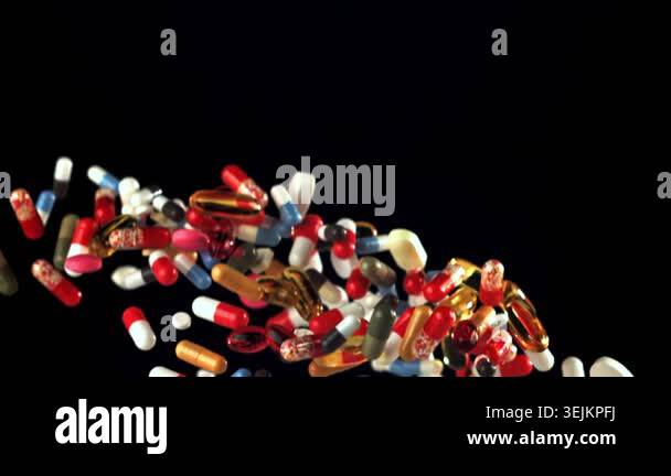 Assorted capsules and tablets tumbling across black background, mixed ...