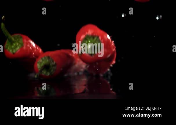 Red peppers tumbling across dark surface, dramatic highcontrast motion ...