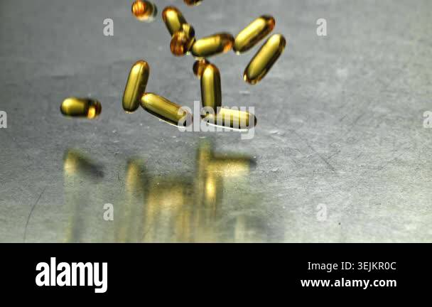 Golden softgel capsules scattered over metal, closeup of oilfilled ...