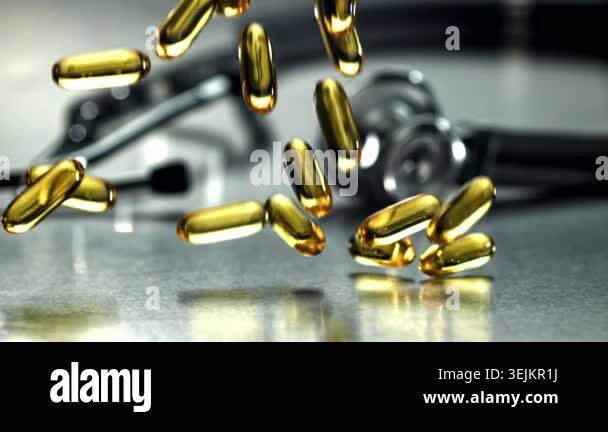 Golden softgel capsules on stainless surface scattered Filmed on a high ...