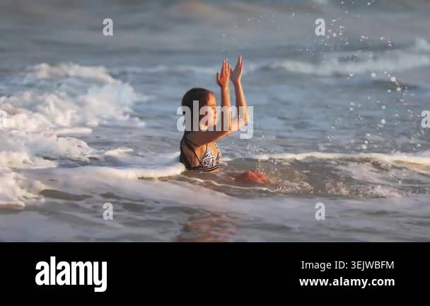 Cheerful wet dark-haired girl with wet hair in a bright leopard bikini ...