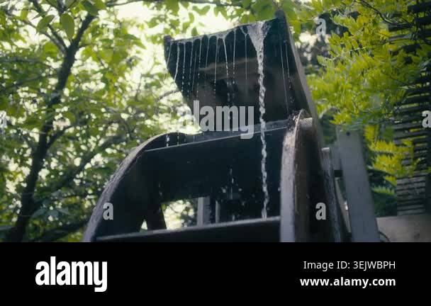 Low angle view of a traditional wooden water wheel in a peaceful garden ...