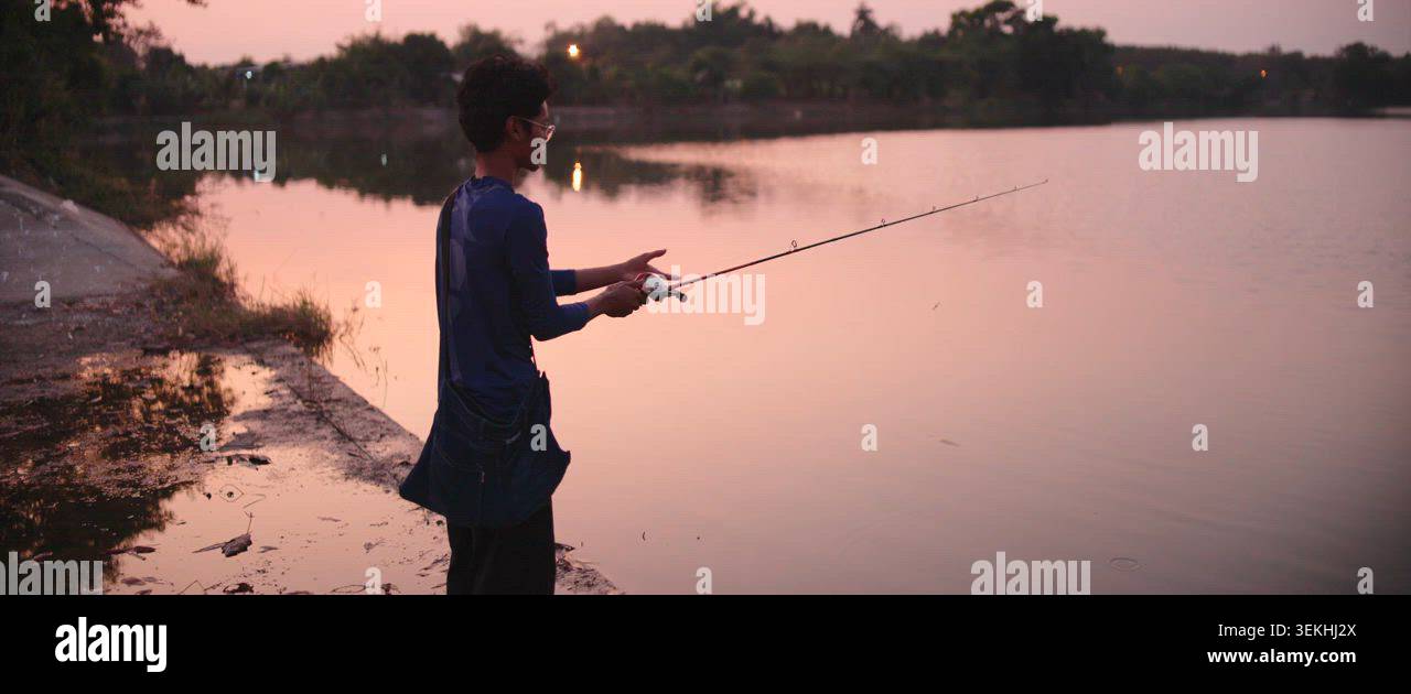 Silhouette of teenager fisherman casting fishing rod during sunset ...