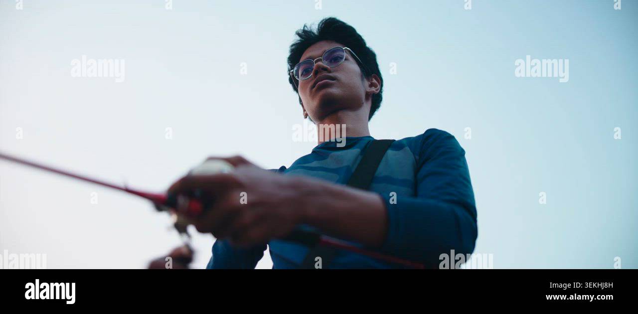 Low angle view of a young man with glasses casting a fishing rod Stock ...