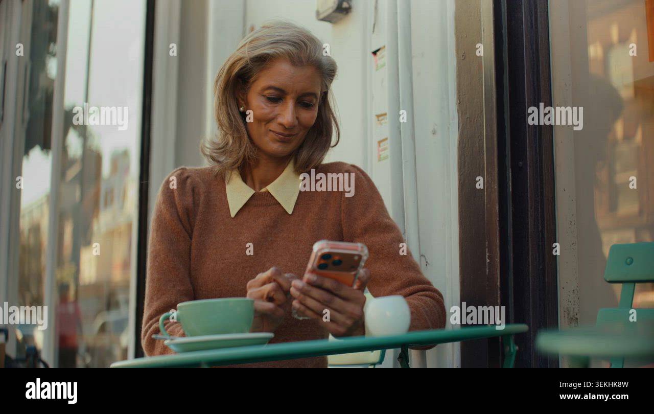 mature Woman at Cafe Table With Phone and Coffee in City Setting Stock ...
