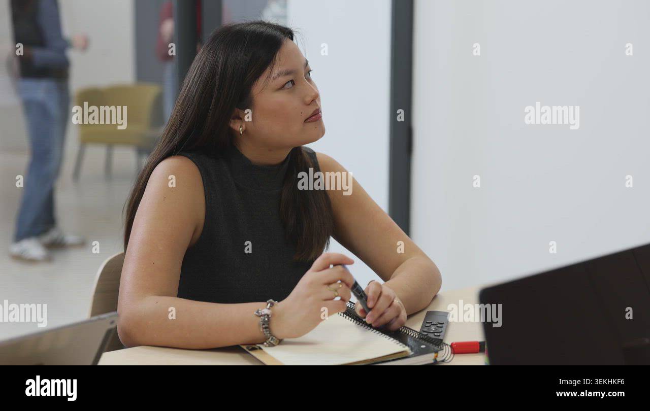 Young asian woman student listening and laughing in a classroom lectur ...