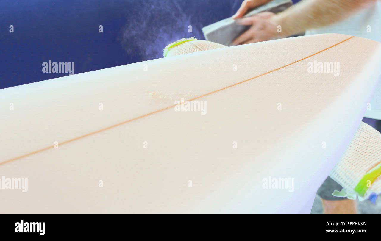 Static handheld close-up shot of a shaper sanding nose of foam blank ...