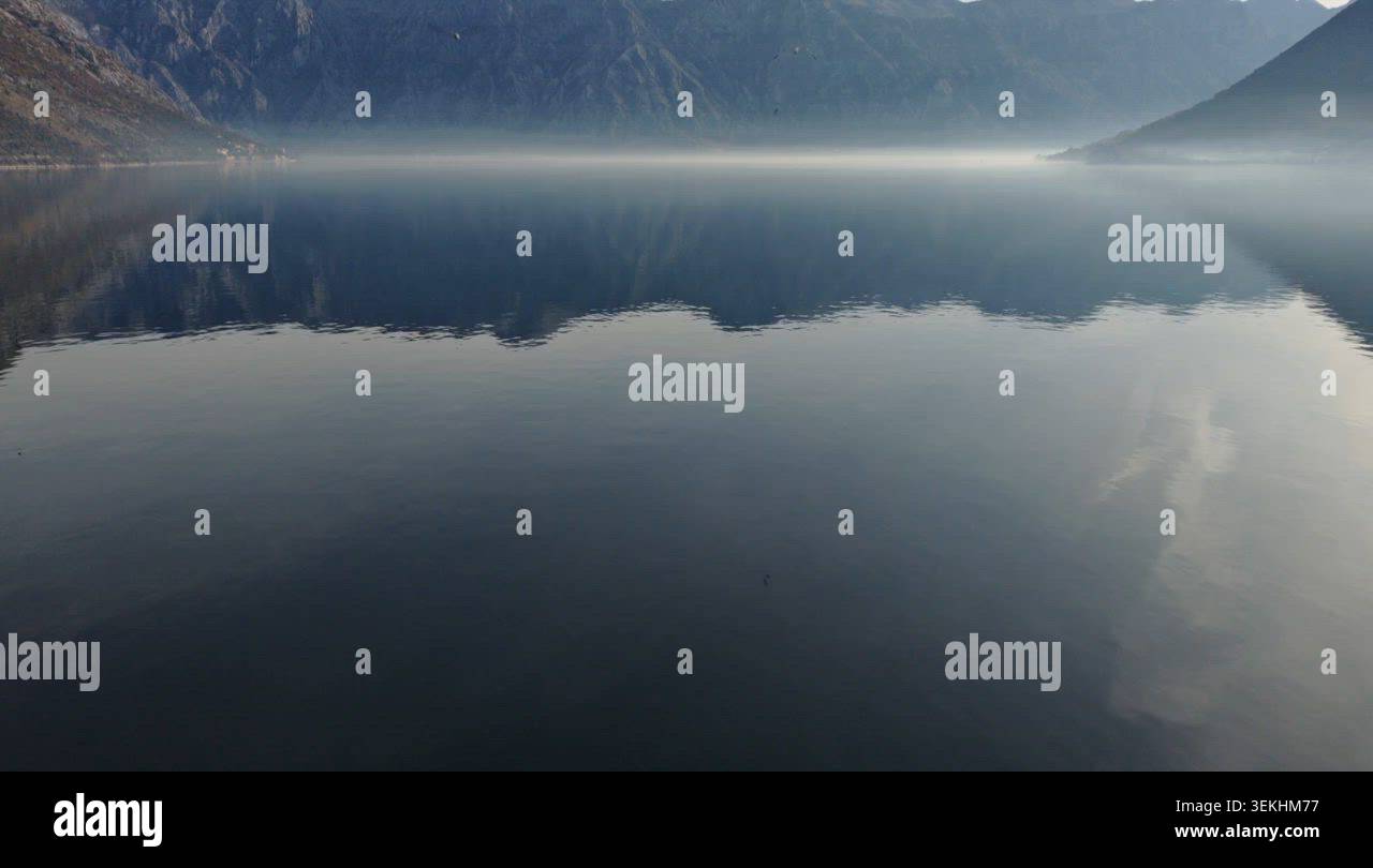 Birds flying over Mountain bay Reflects Surrounding Peaks in Morning ...