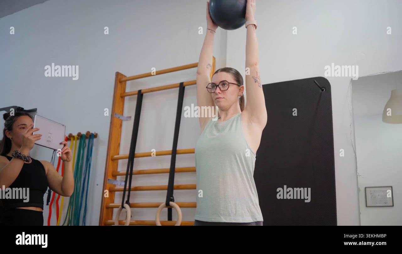 Trainer using a tablet to coach her client with a medicine ball Stock ...