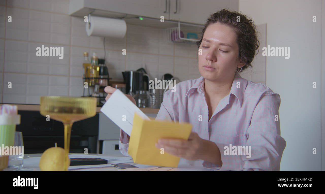 Person opening an envelope and reading a letter with a sad expression ...