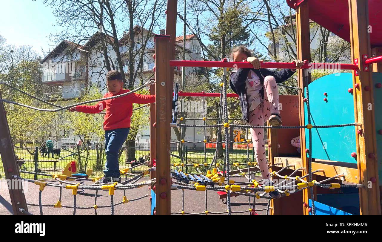 Children playing on a rope climbing frame at an outdoor playground ...