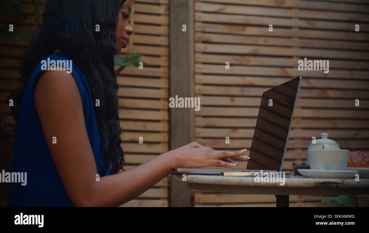 Woman at Table Working on Laptop in Outdoor Setting During Day Stock ...
