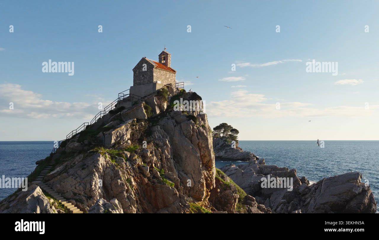 Flock of seagulls flying over the island with a church on top, aerial ...