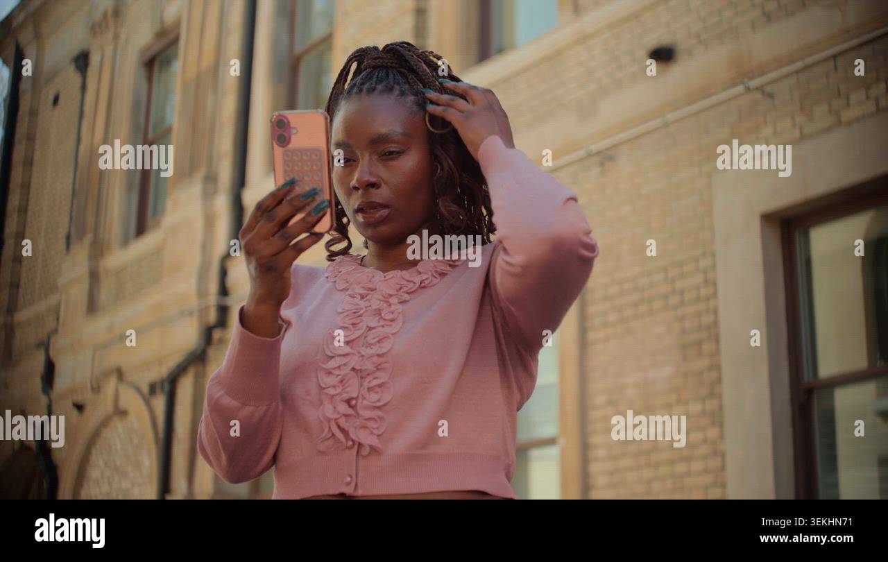 A woman starting a facetime video call outside and old building Stock ...