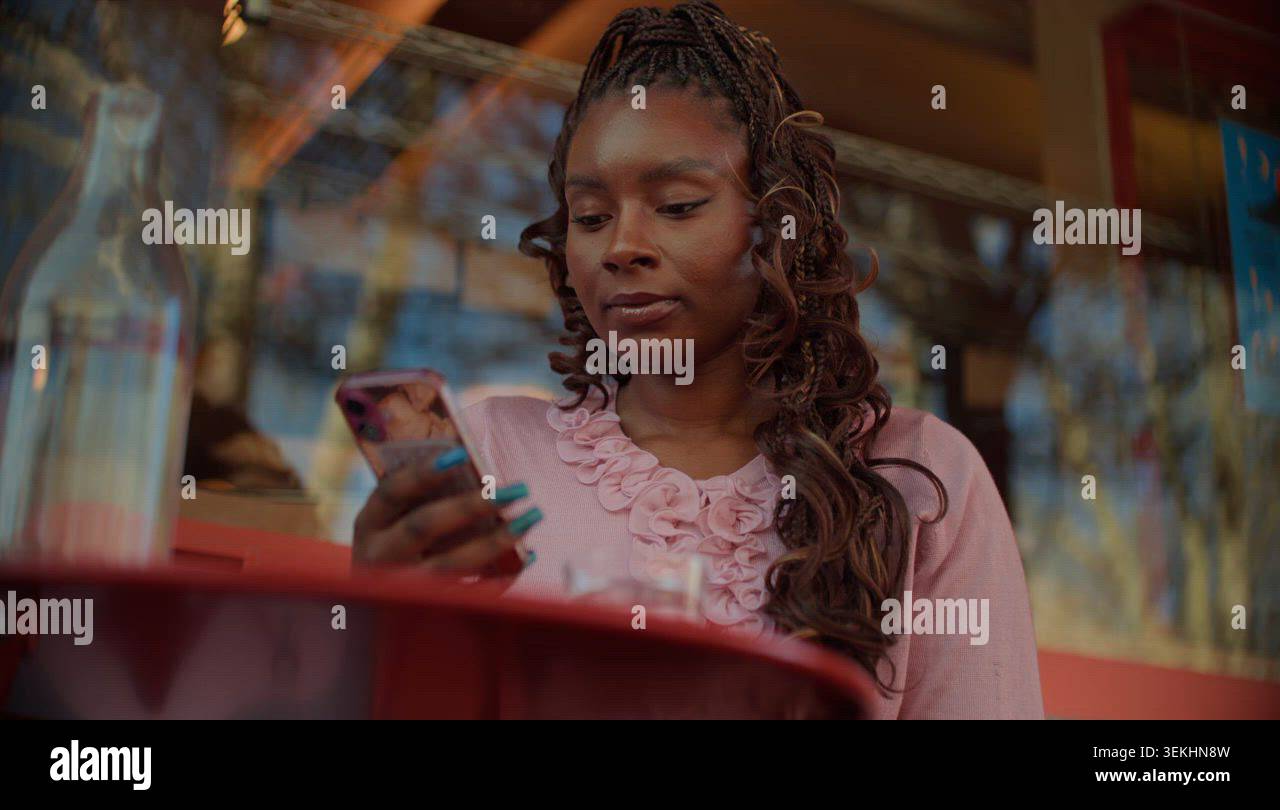 woman at an outdoor cafe table smiling at her phone Stock Video Footage ...