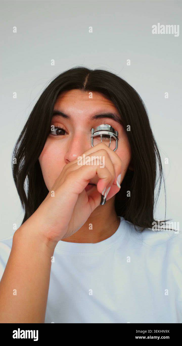 Young woman curling her eyelashes during makeup routine Stock Video ...