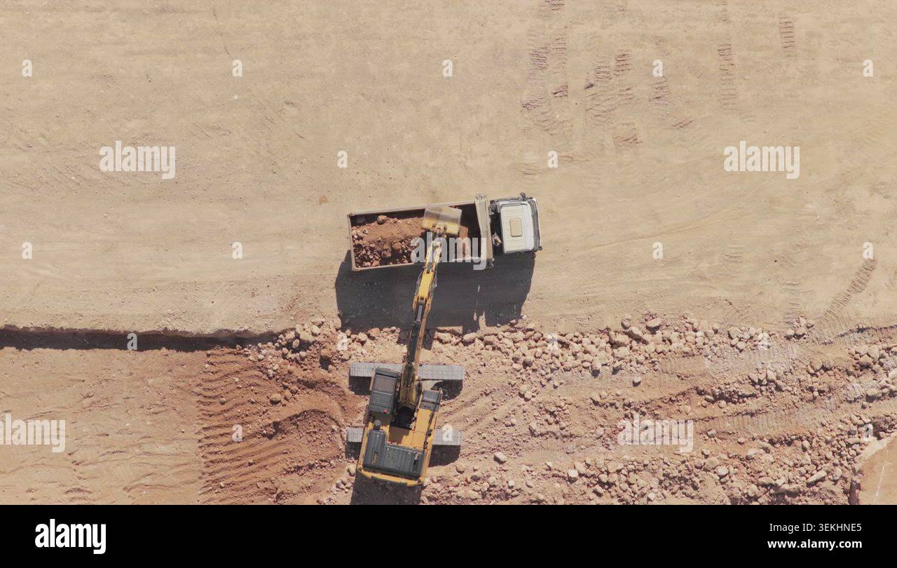 Excavator loading a dump truck with soil at a construction site Stock ...
