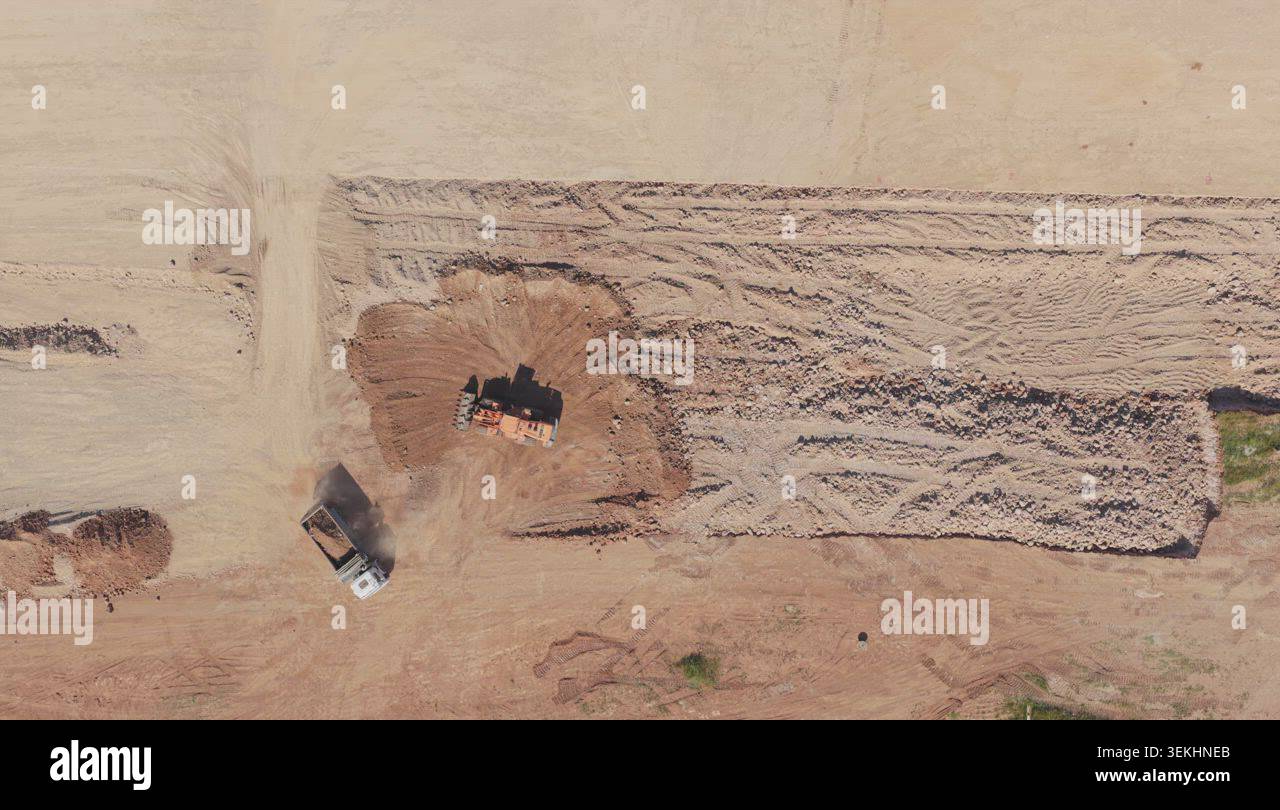 Aerial view of bulldozer pushing earth and truck transporting soil ...