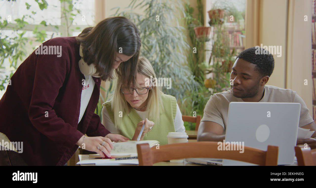 Diverse students studying and laughing together in university library ...