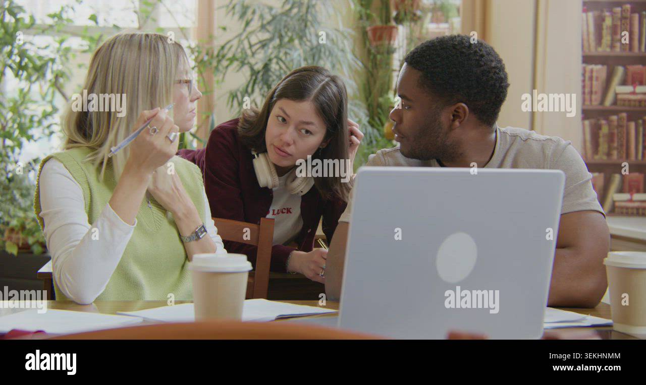 Diverse students collaborating on a laptop in the university library ...