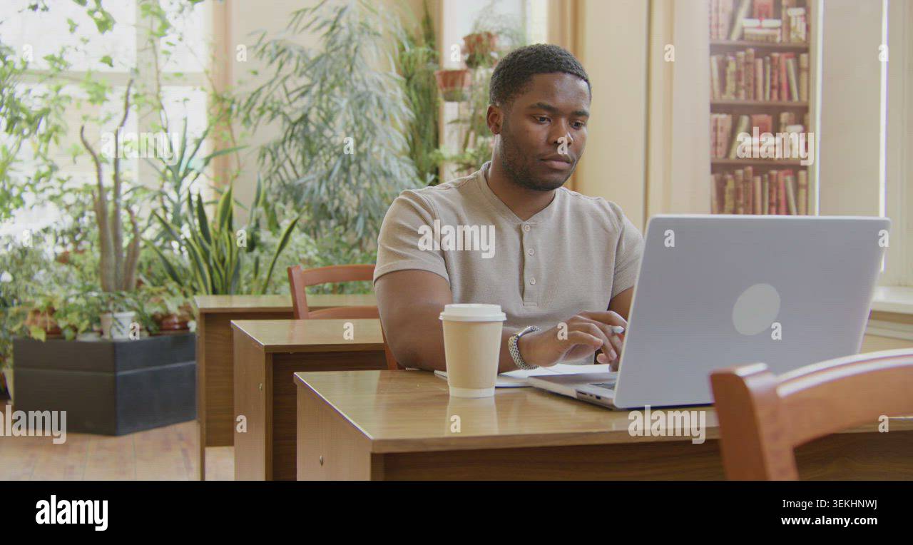 Student typing on a laptop and studying in the university library Stock ...