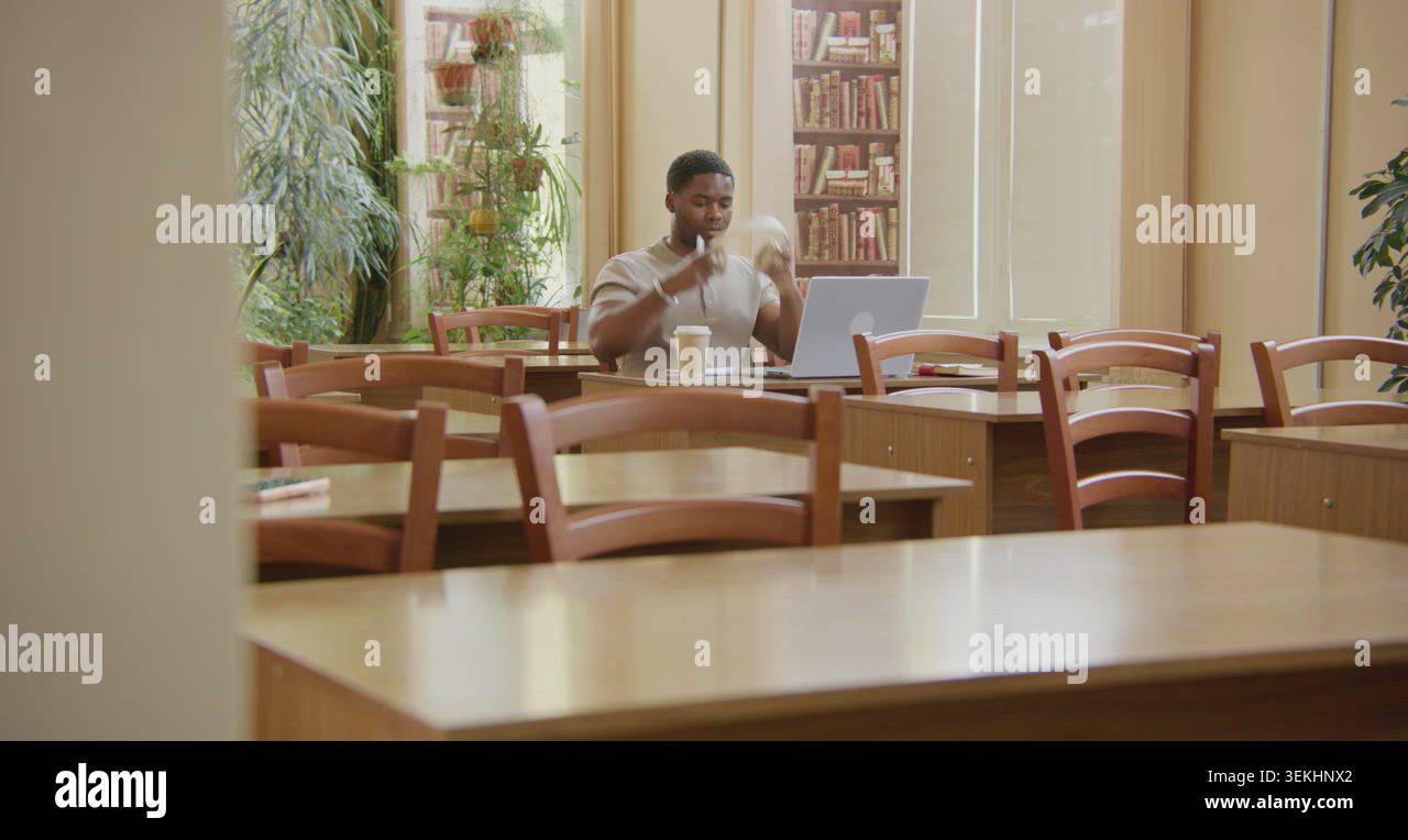Student putting on headphones studying in library Stock Video Footage ...