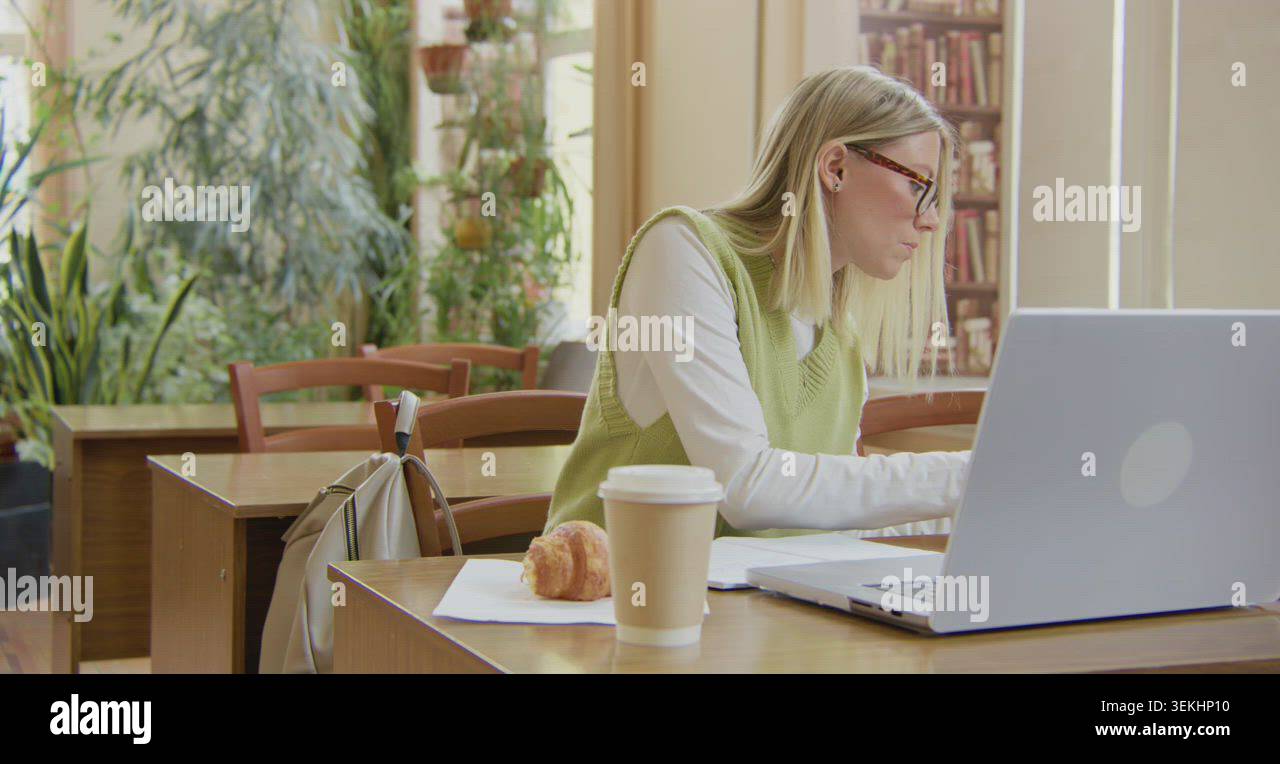 Student taking notes using laptop in a university library Stock Video ...