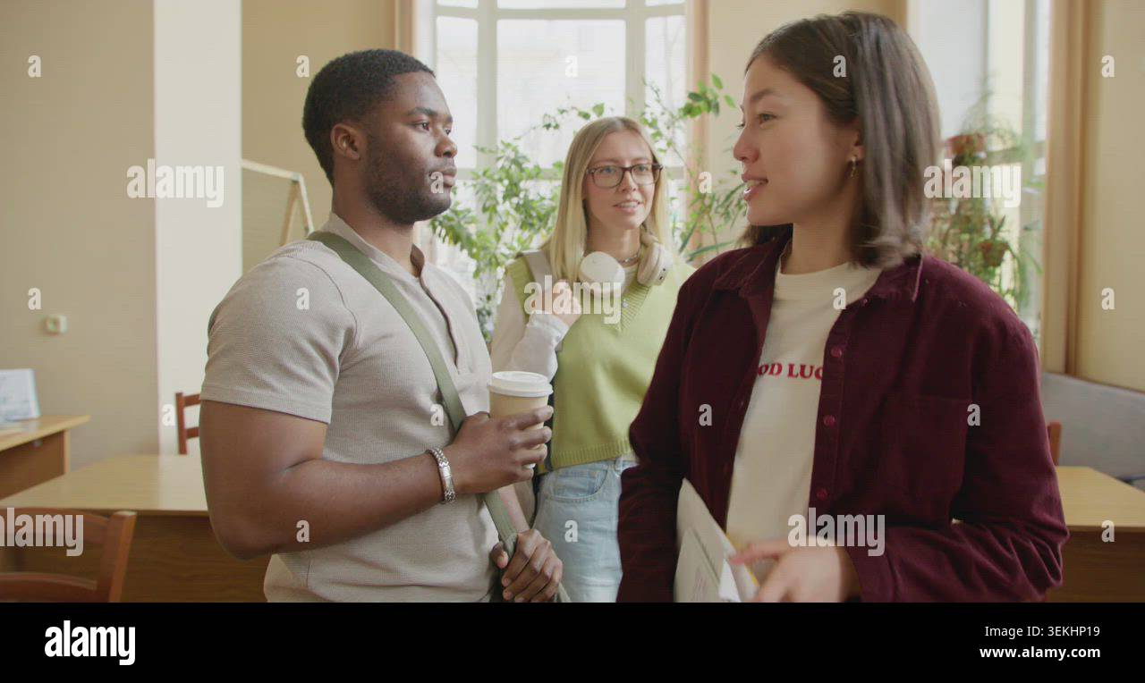 Diverse students chatting and walking in a university library Stock ...