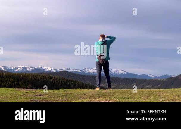 Man with camera bag trekking in mountains, scouting location for ...